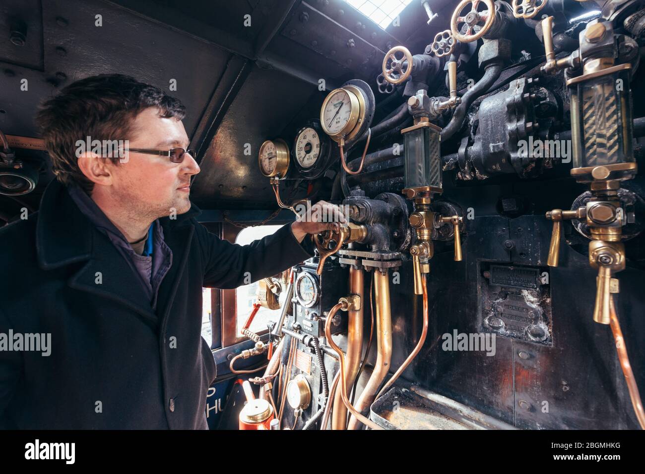 A man controls the dials and levers in the cab Working British steam ...