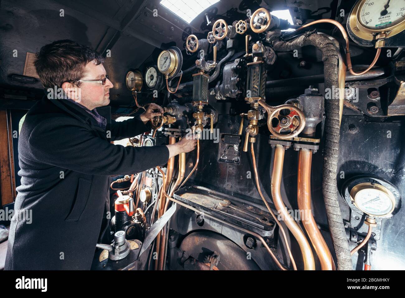 A man controls the dials and levers in the cab Working British steam ...