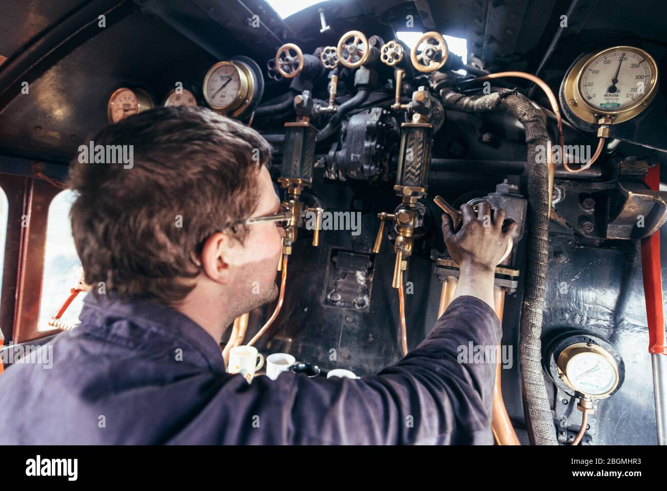 A man controls the dials and levers in the cab Working British steam ...