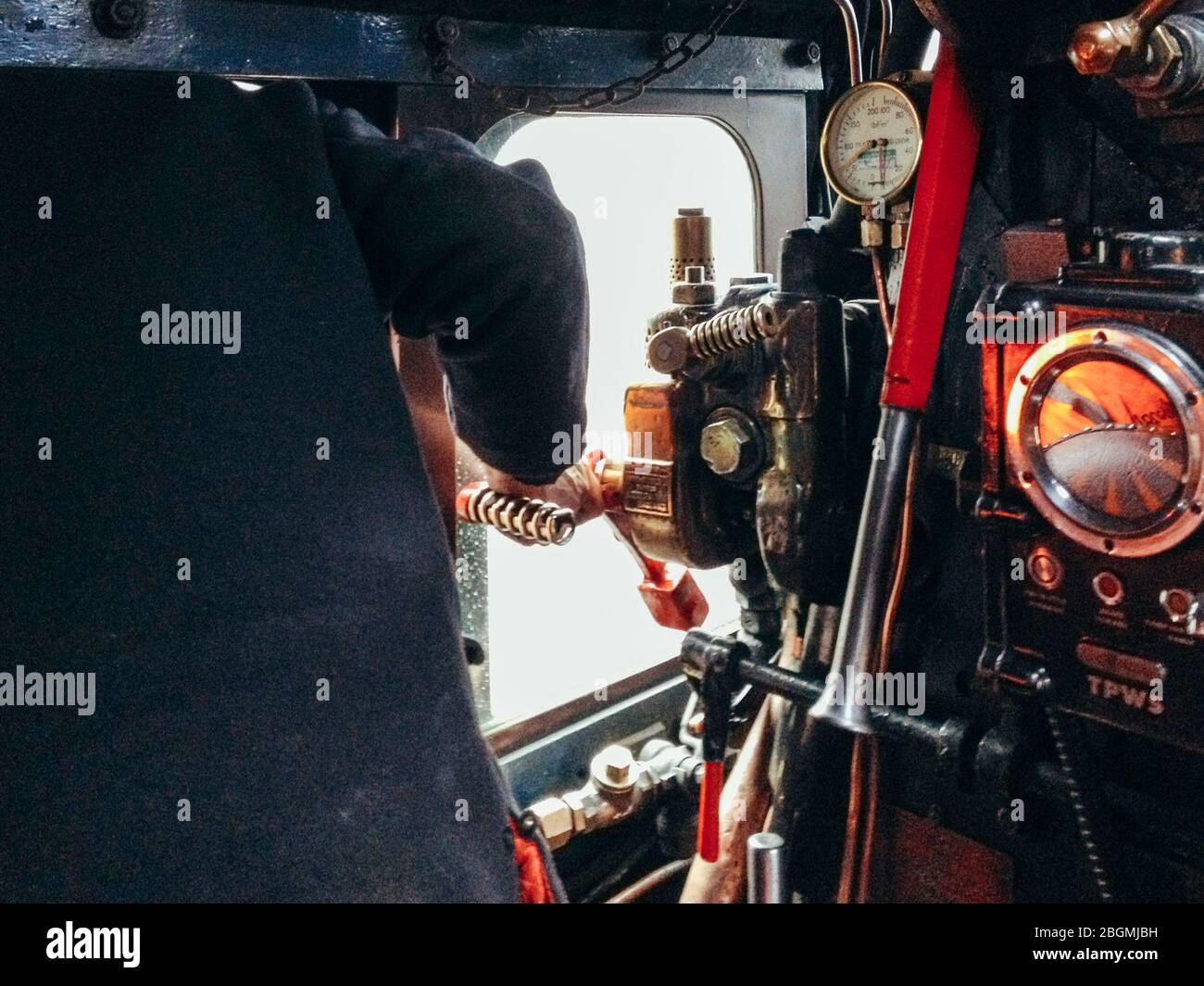A man in the cab looks out of the window whilst holding a lever Working ...
