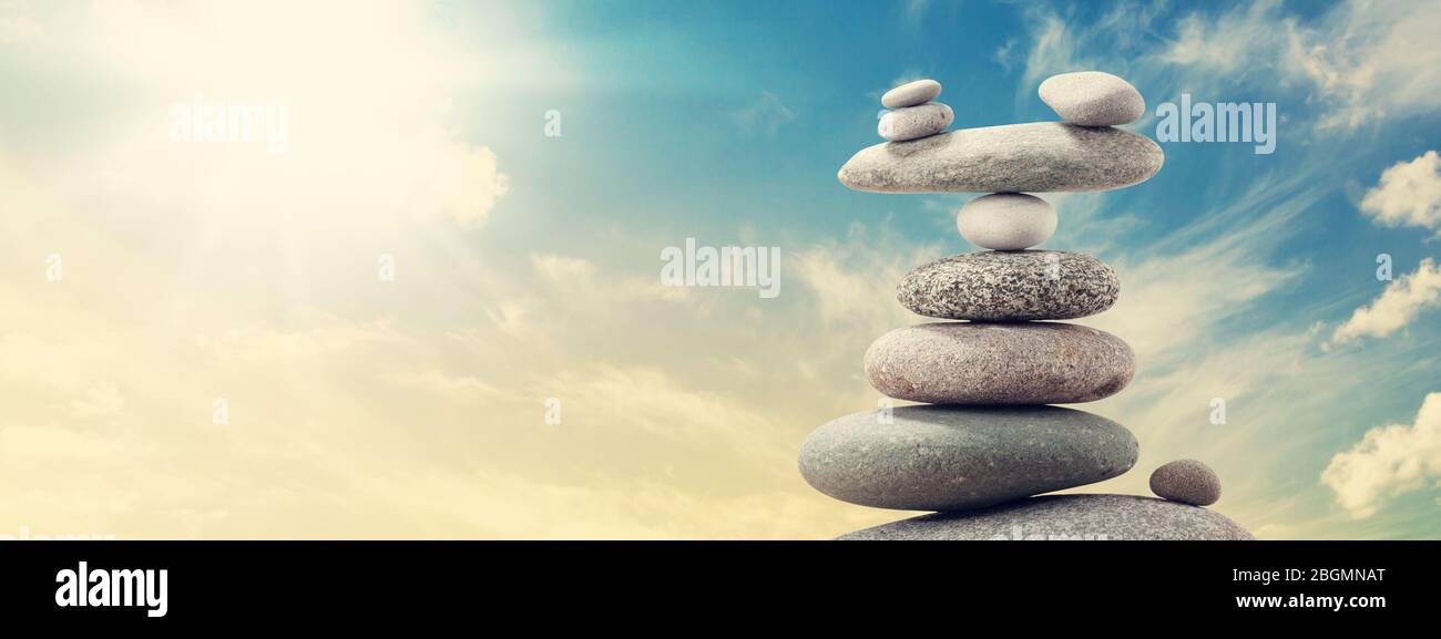 Pyramid of sea pebbles over a sunny sky. Life balance and harmony ...