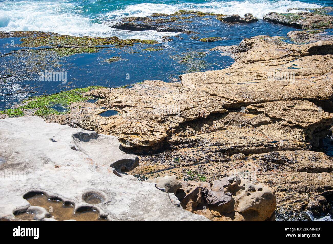 Coastal scene. Colourful rock pools formed by wind and sea erosion ...