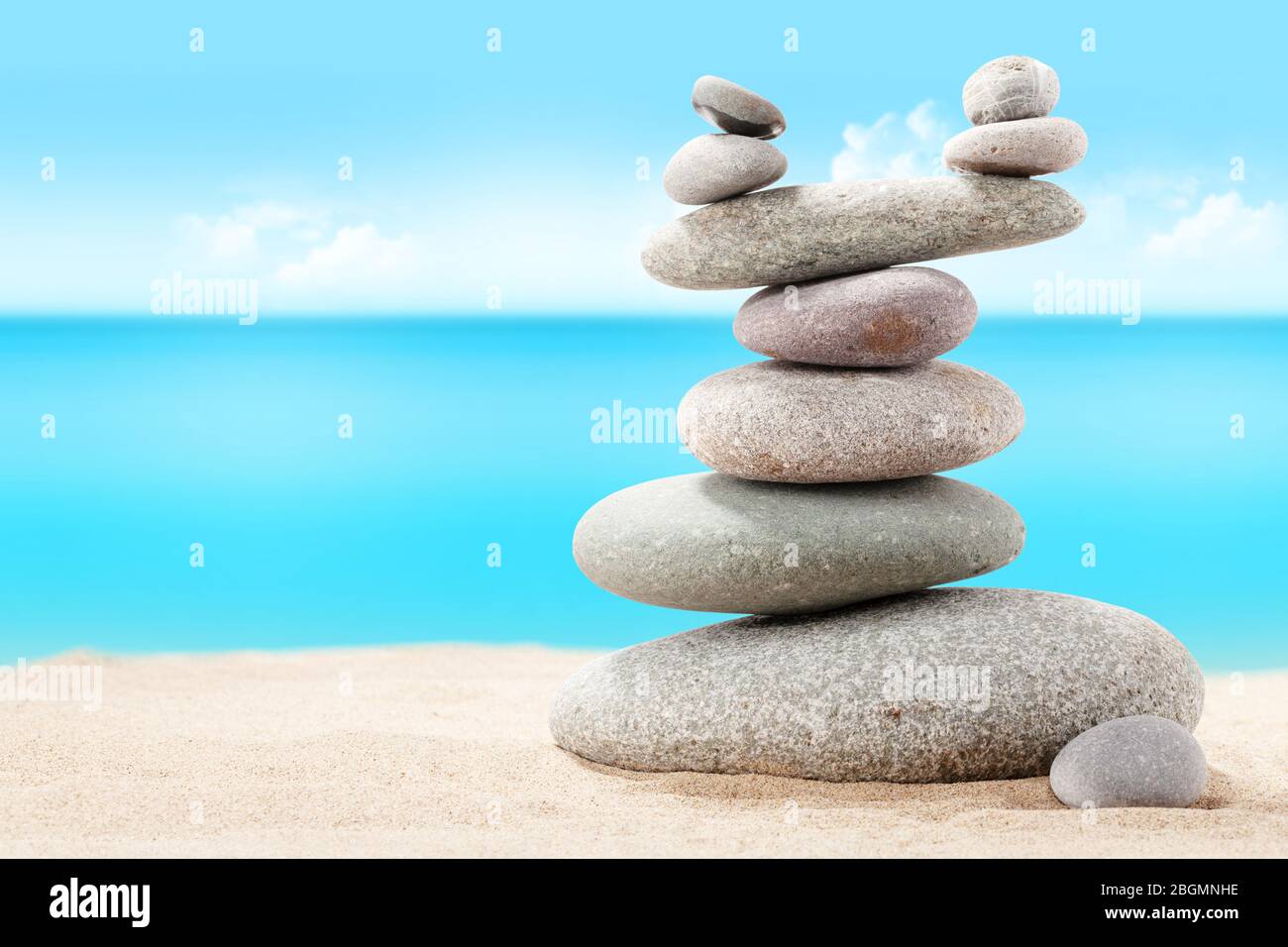 Pyramid of sea pebbles on a sunny sand beach. Life balance and harmony ...