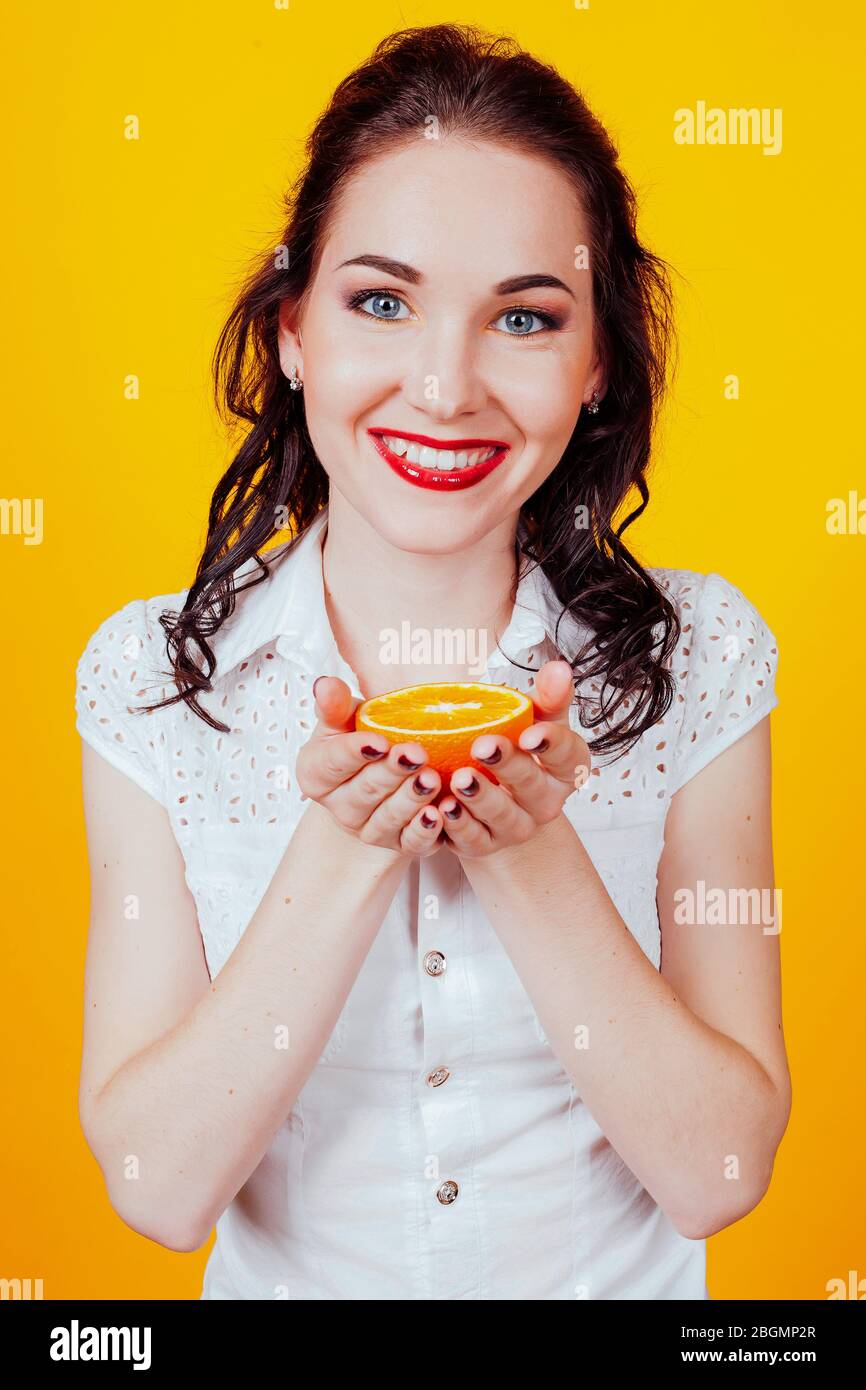Beautiful woman holds an orange and smiles Stock Photo - Alamy