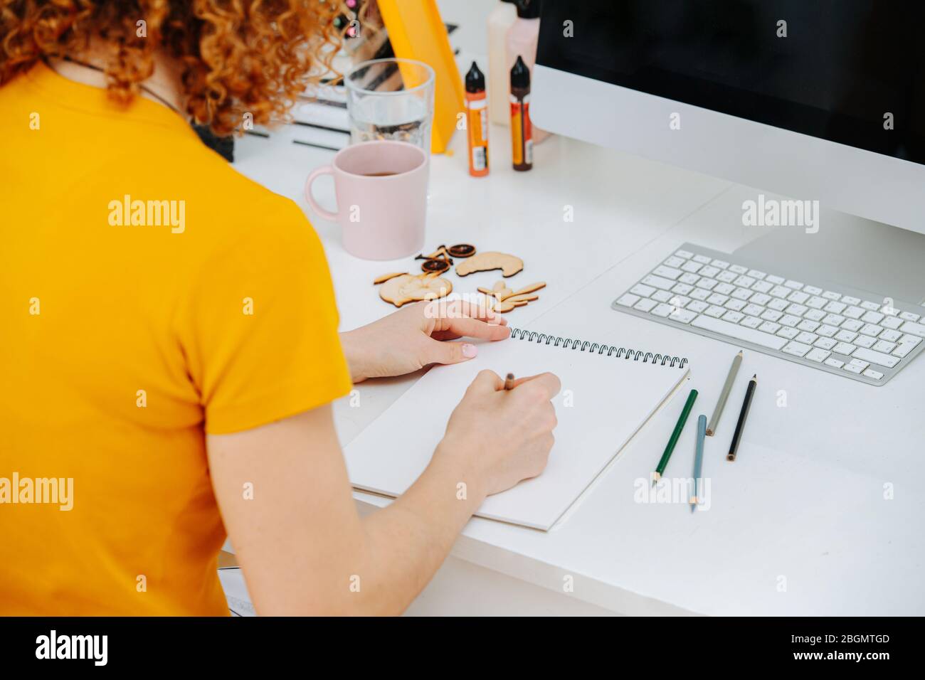 Artist woman drawing behind work desk in her notepad with crayon. From ...