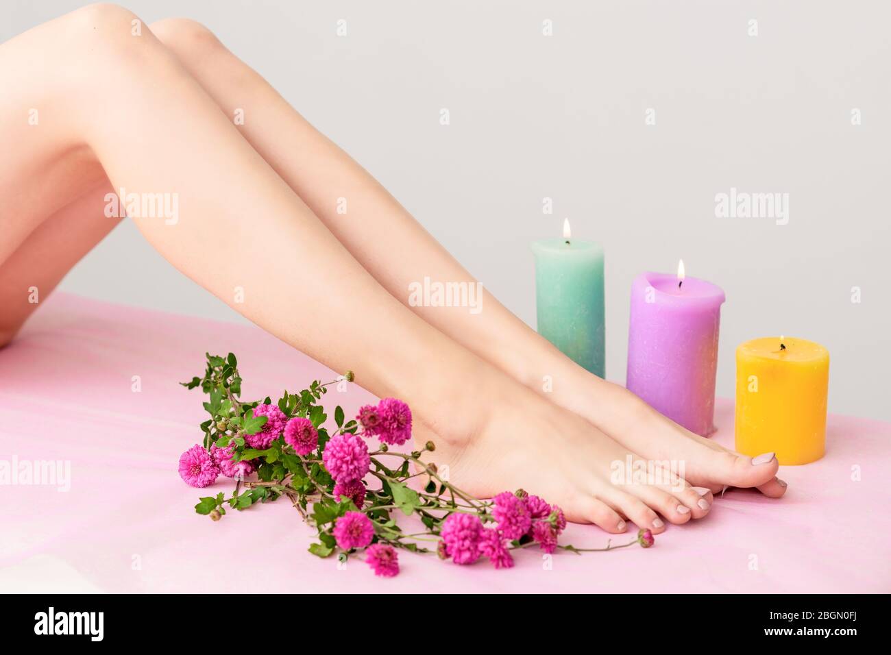 Beautiful female legs with smooth skin decorated with burning candles ...