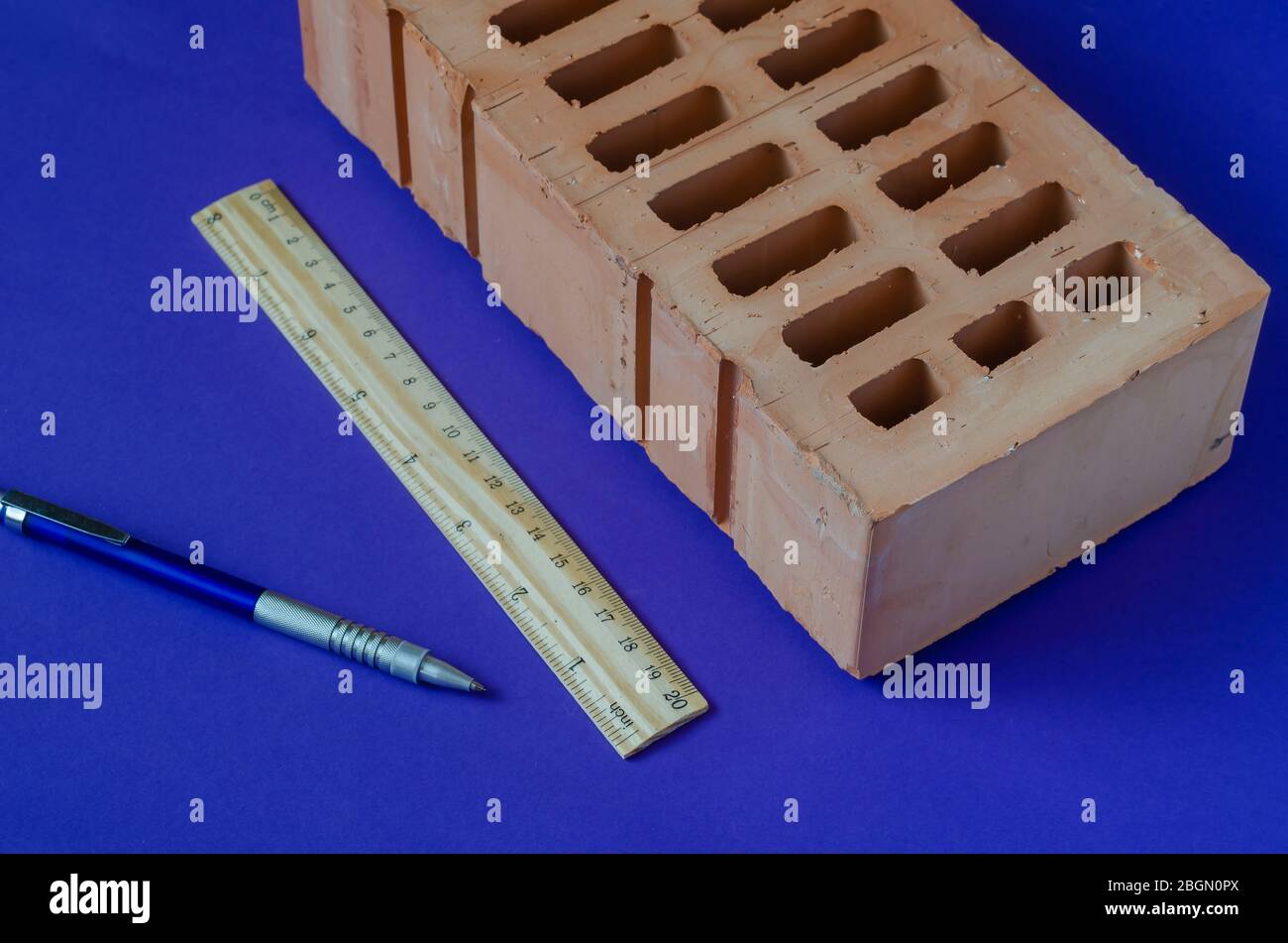 Brick, pen and wooden ruler. Single brick and stationery on a blue ...