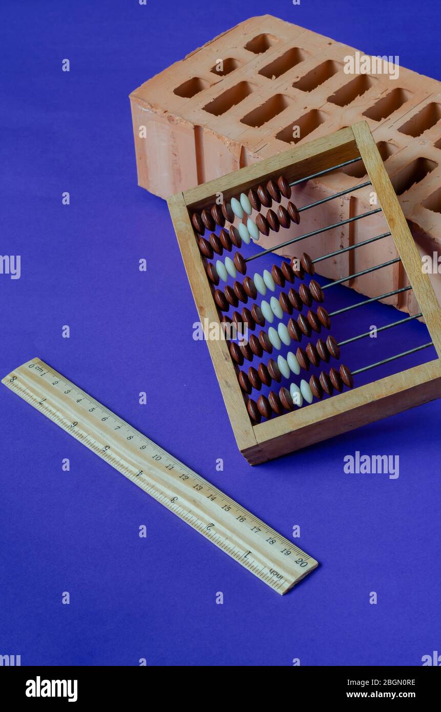 Brick, wooden abacus and ruler. Single brick and stationery on a blue ...