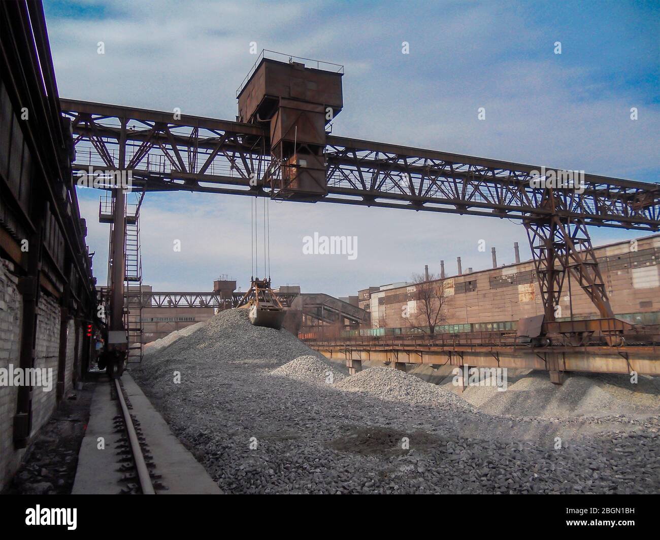 The process of loading crushed stone with a gantry crane. A rusty grab ...