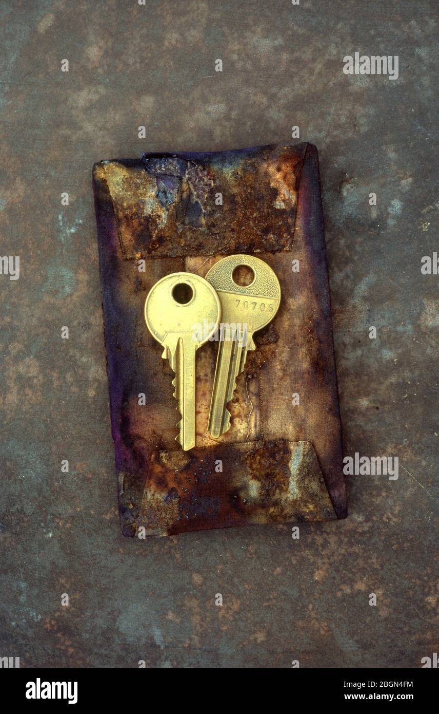 Two vintage brass Yale type door keys lying on stained and burnt wood ...