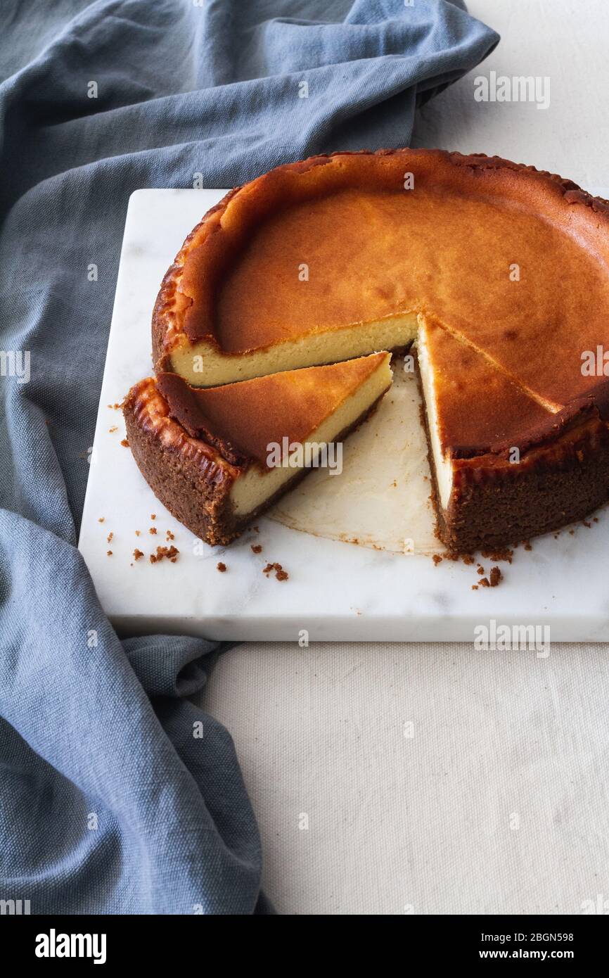 Baked ricotta cheesecake with cut slices on a piece of white marble ...