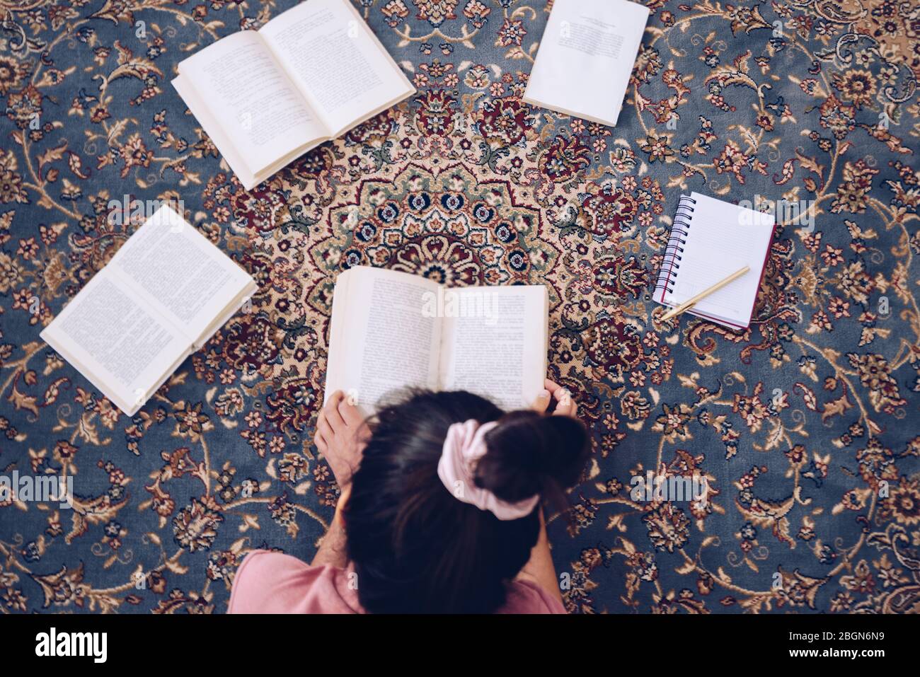 Young woman lying on carpet and reading book Stock Photo - Alamy