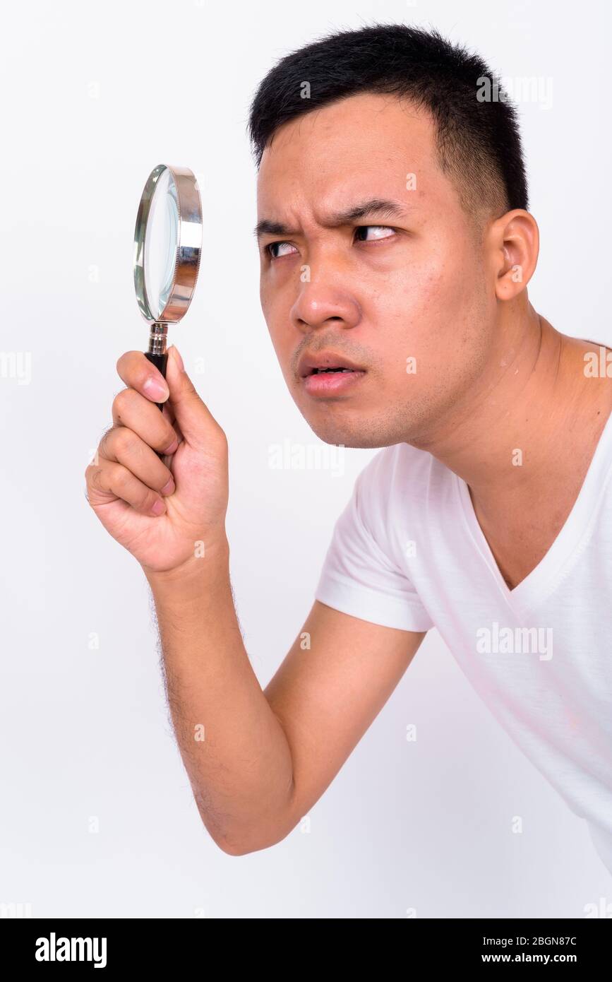 Face of young Asian man using magnifying glass Stock Photo - Alamy