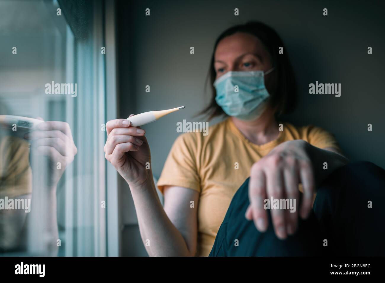 Woman in self-isolation measuring body temperature electronic digital ...