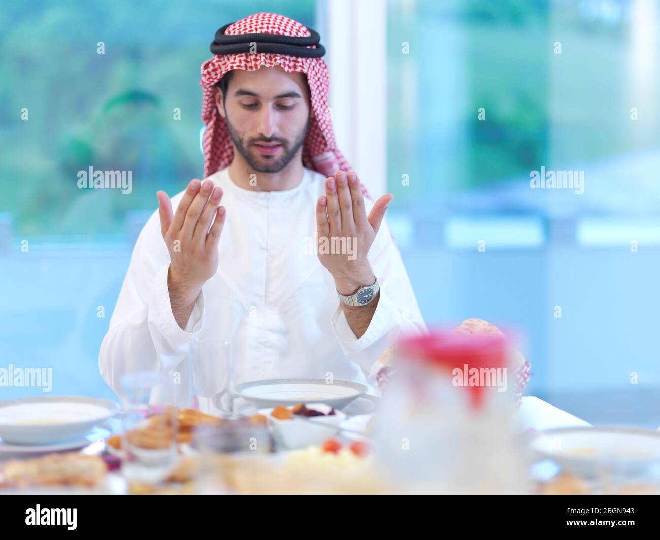 young arabian muslim man making traditional prayer to God, keeps hands ...