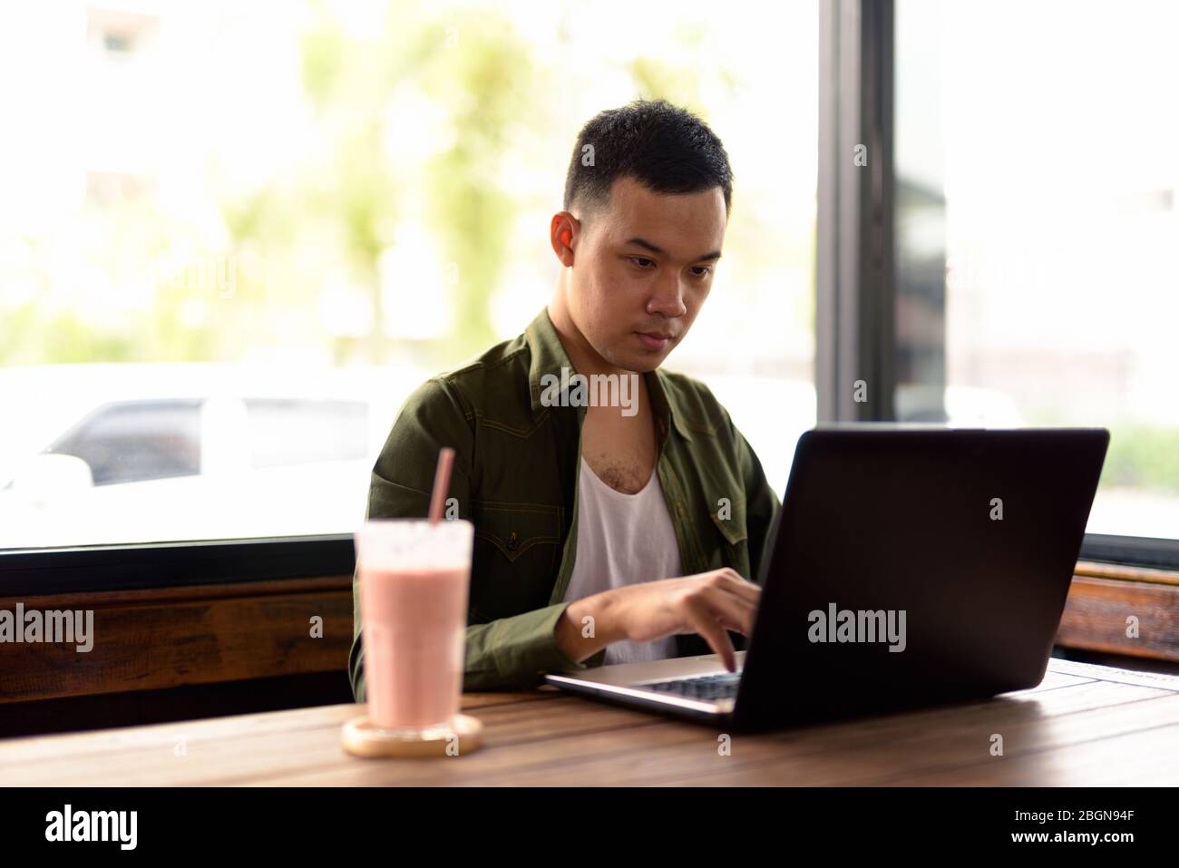 Young Asian man using laptop at the coffee shop Stock Photo - Alamy