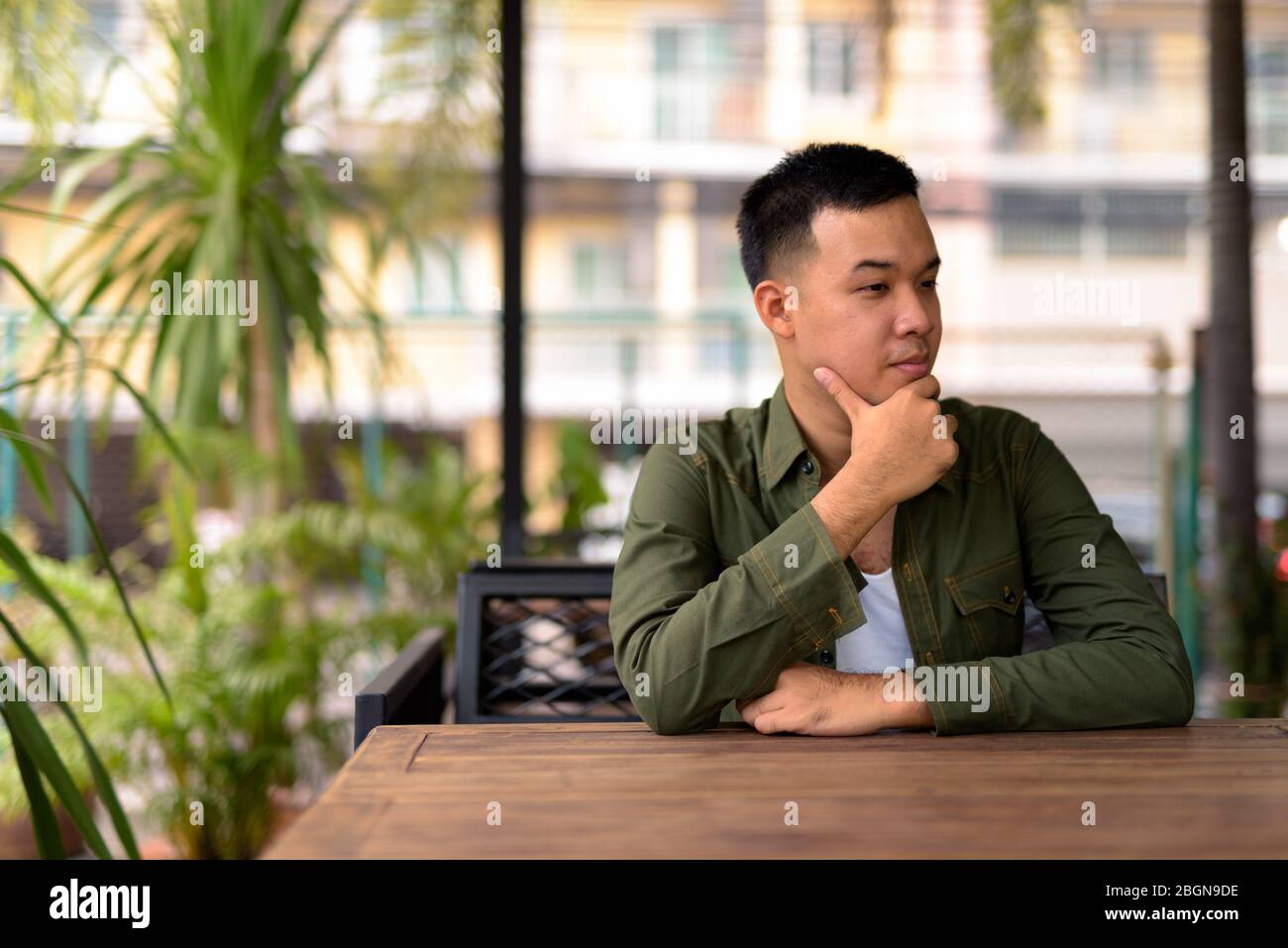 Young Asian man thinking at the coffee shop Stock Photo - Alamy