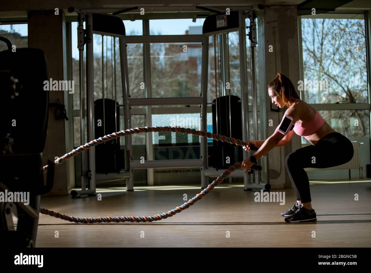 Pretty young woman with battle ropes exercise in the fitness gym Stock ...