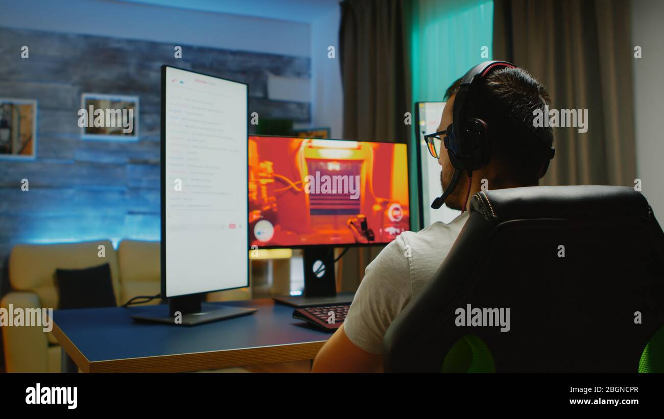 Young man with headphones talking on chat while playing shooter games ...