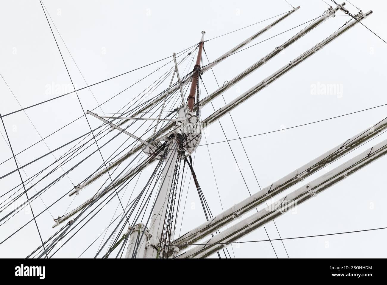 Masts and yards of an old sailing ship are under white winter sky ...