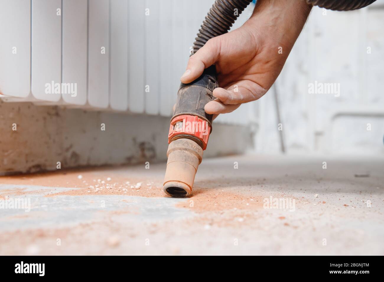 Worker vacuuming debris and dust from floor after drilling concrete ...