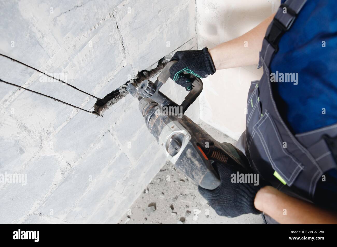 Builder worker man with hammer drill perforator equipment making hole ...