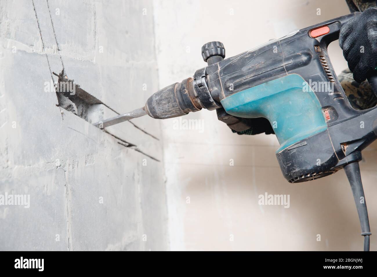 Builder worker man using jackhammer to drill into construction wall for ...