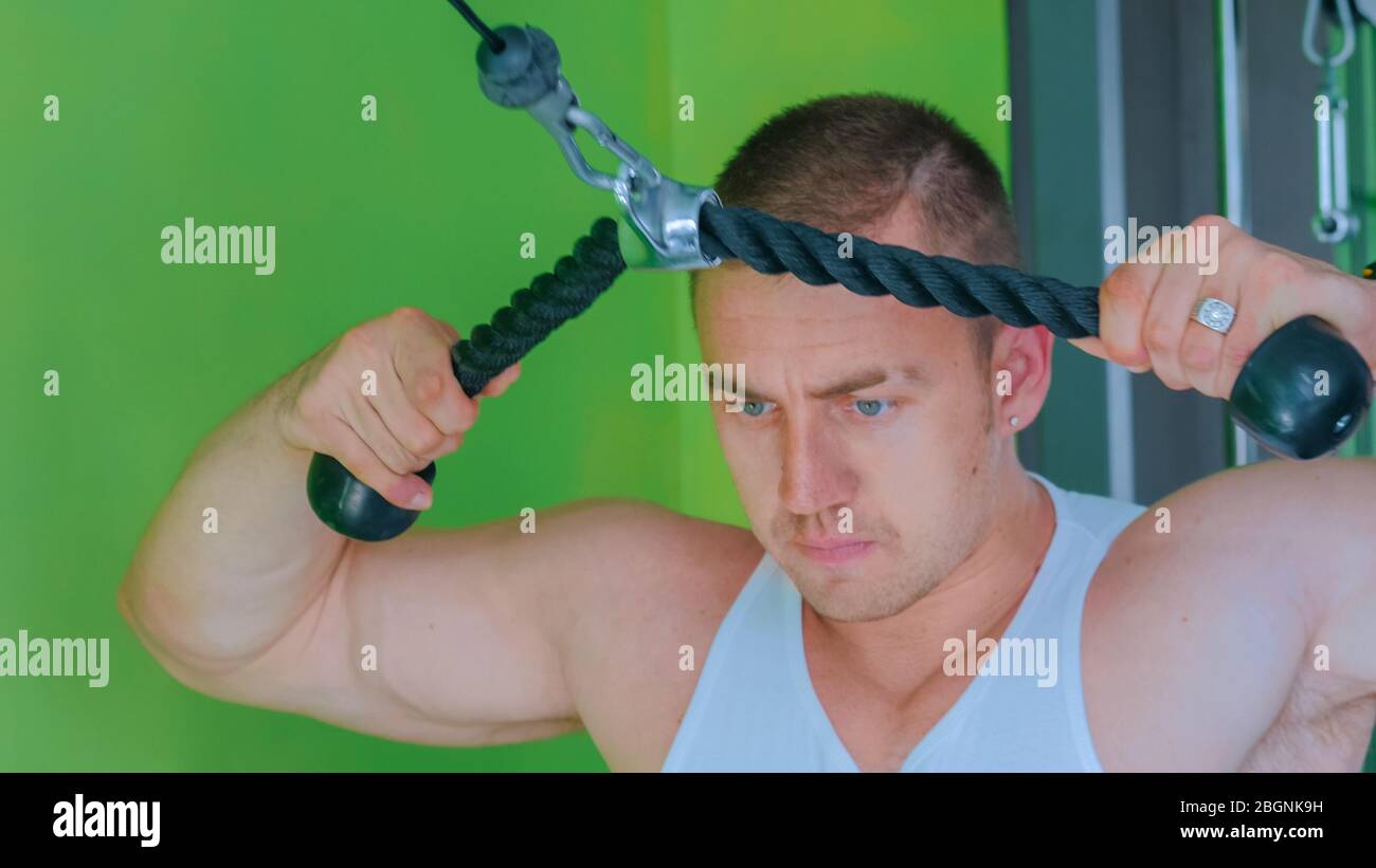 Athletic young man working out on fitness exercise equipment at gym ...