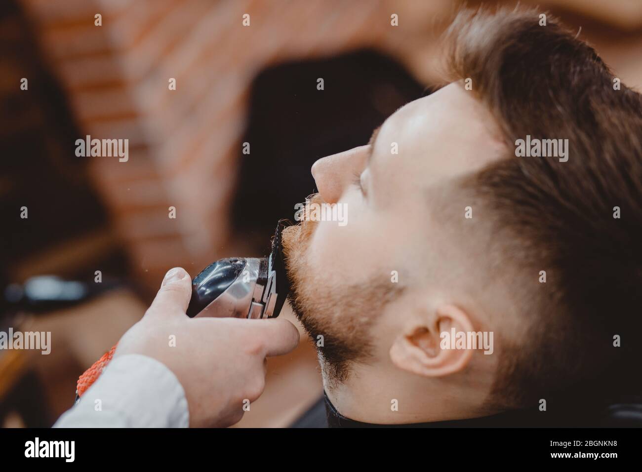 Barber shearing beard to man in barbershop framing hairline. electric ...