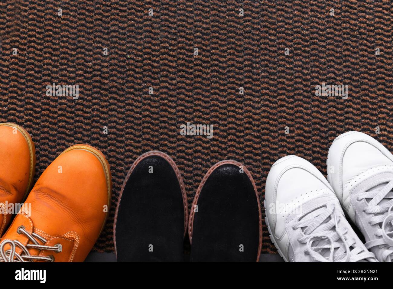 Different men's and women's shoes, pair of sneakers on shoe mat, top ...