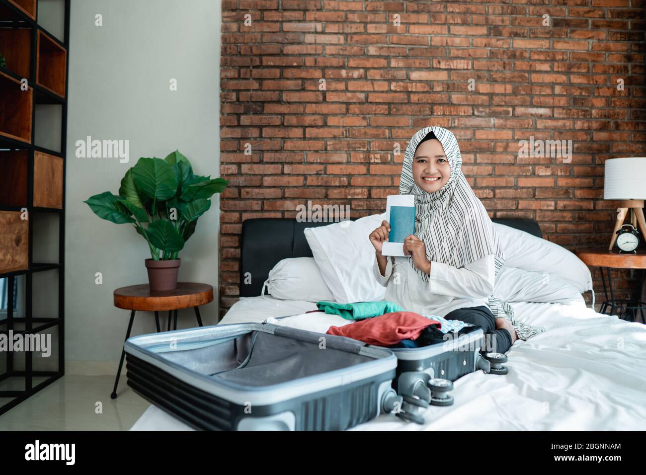 woman wear hijab preparing for holiday holding passport while packing ...