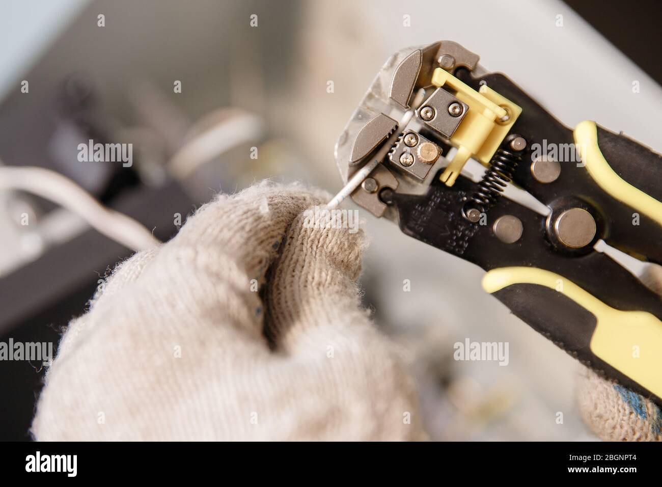 Master electrician with professional tool for removing insulation from ...