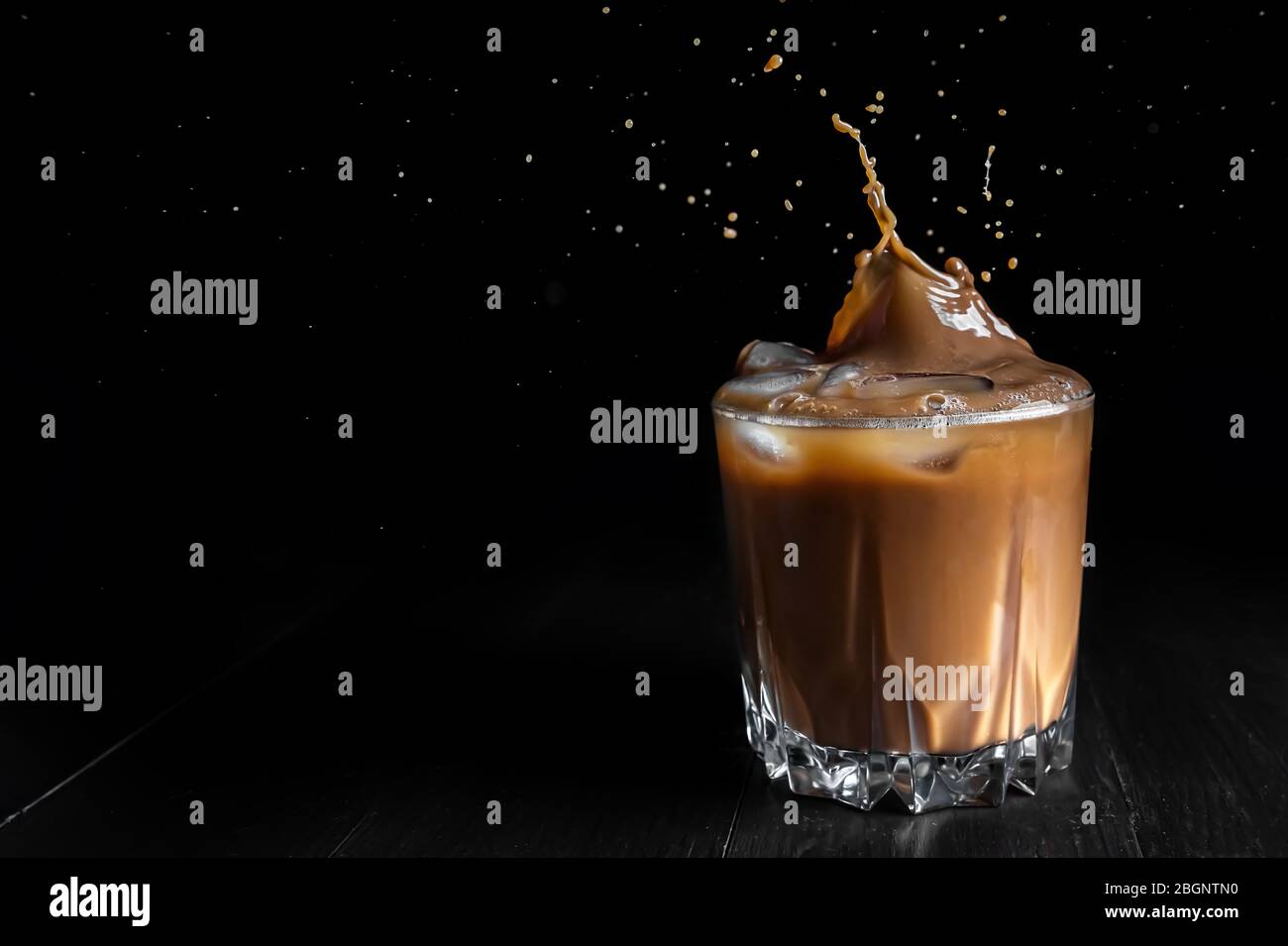 Splash of ice coffee drink on a brown background. cup with ice cubes ...