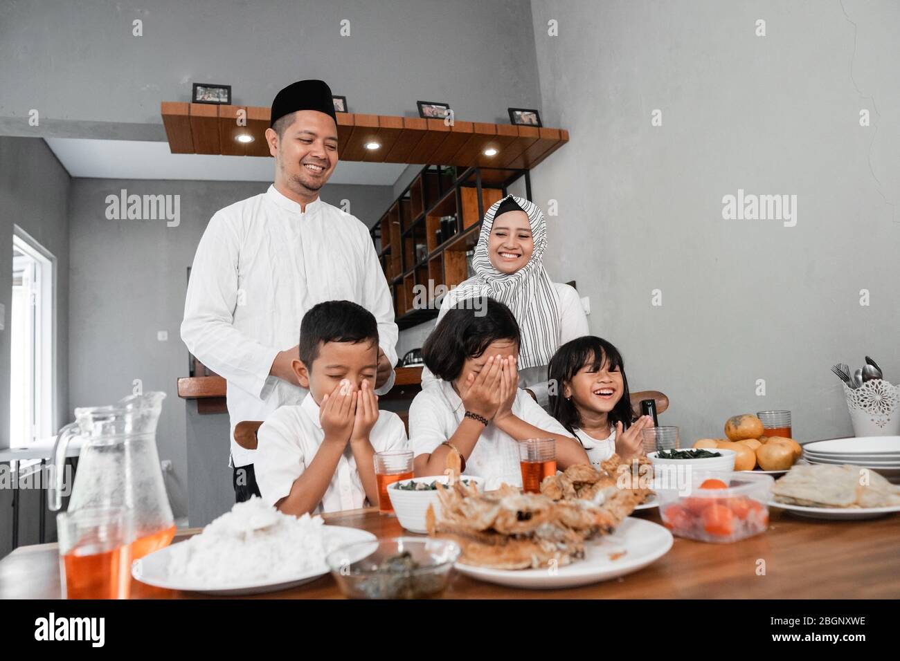 muslim family praying before eating their food. breaking the fast or ...