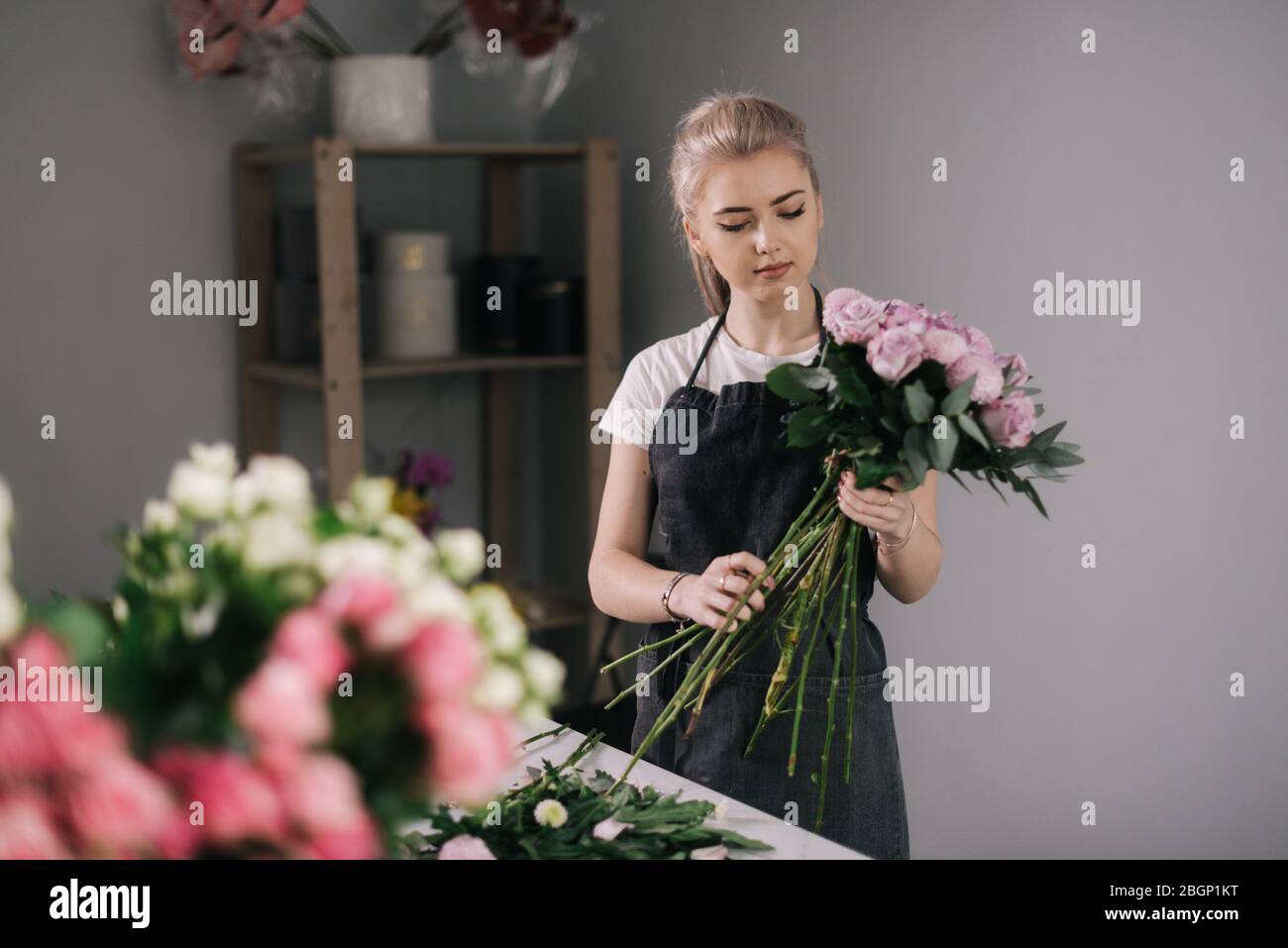 Professional young woman florist wearing apron making floral ...