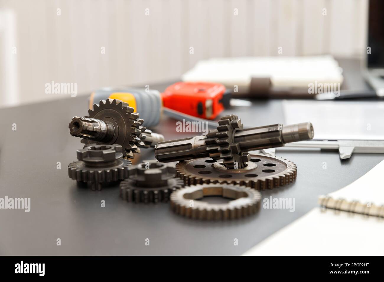 Gear with machine part on engineer desk Stock Photo - Alamy