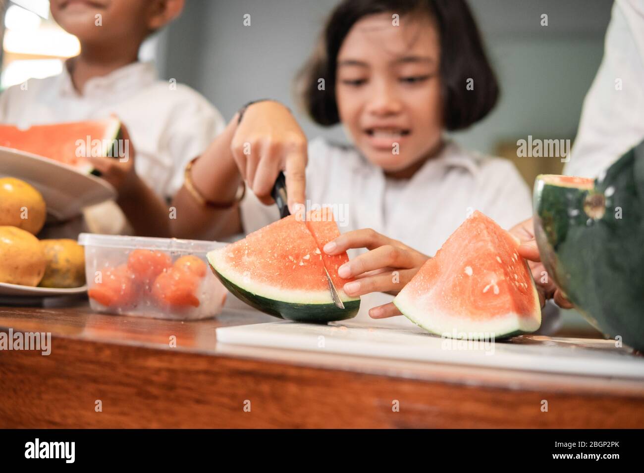 kid slicing watermelon using knife on chopping board Stock Photo - Alamy