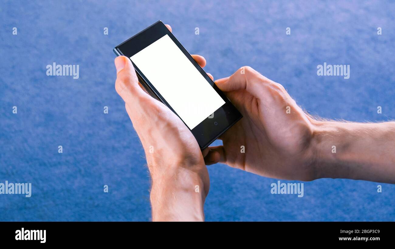 Man looking at smartphone phone with white blank screen. Close up shot ...