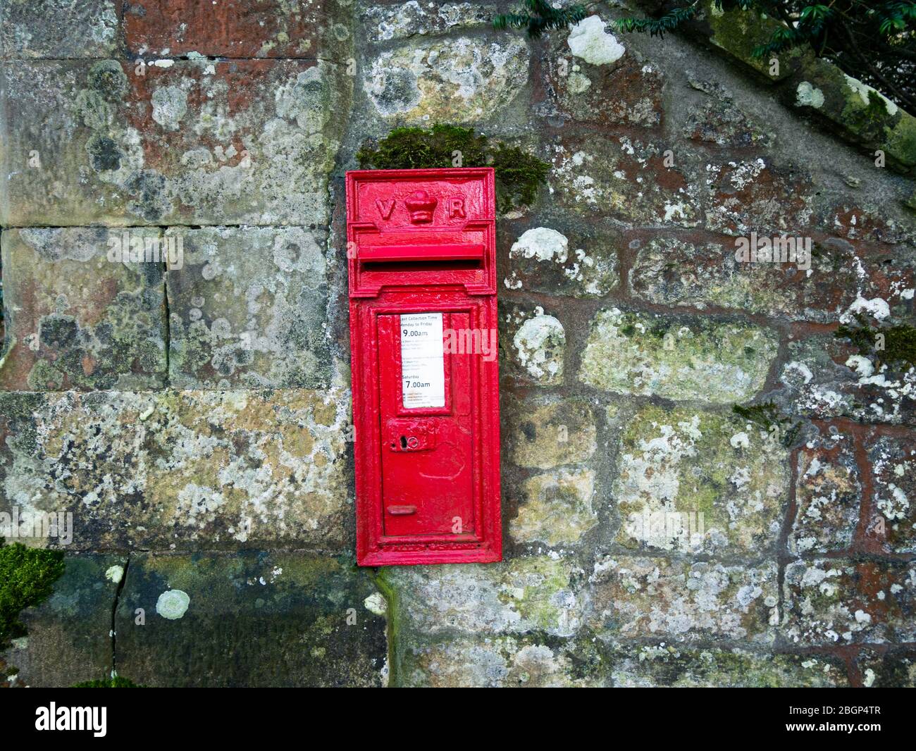 A Queen Victoria era red post box installed in a wall in Northumberland ...