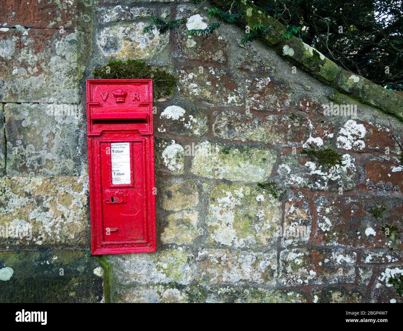 A Queen Victoria era red post box installed in a wall in Northumberland ...