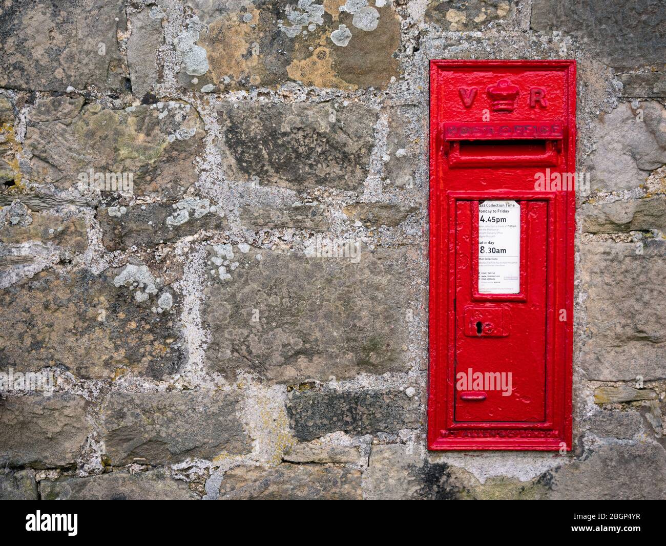 A Queen Victoria era red post box installed in a wall in Northumberland ...