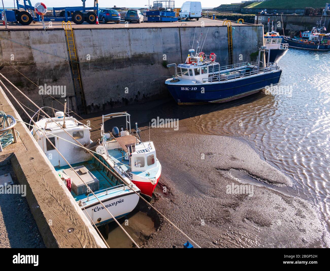 Boats at low tide in the harbour in Amble, Northumberland Stock Photo ...