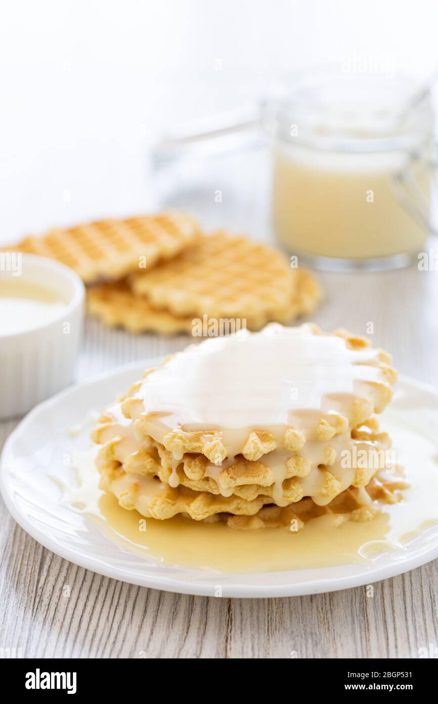 Condensed milk and waffles on a table. Sweet dessert Stock Photo - Alamy