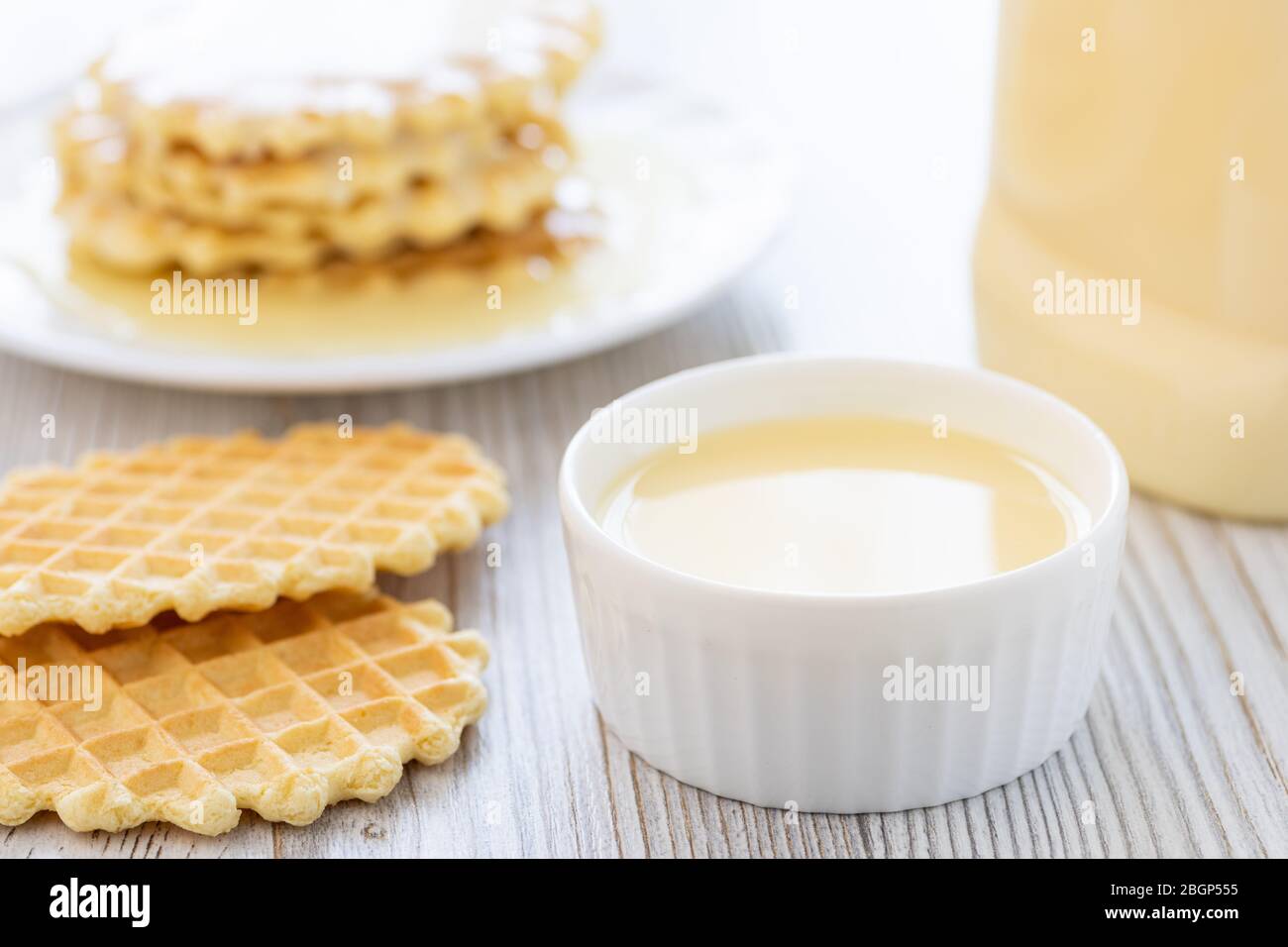 Condensed milk and waffles on a table. Sweet dessert Stock Photo - Alamy