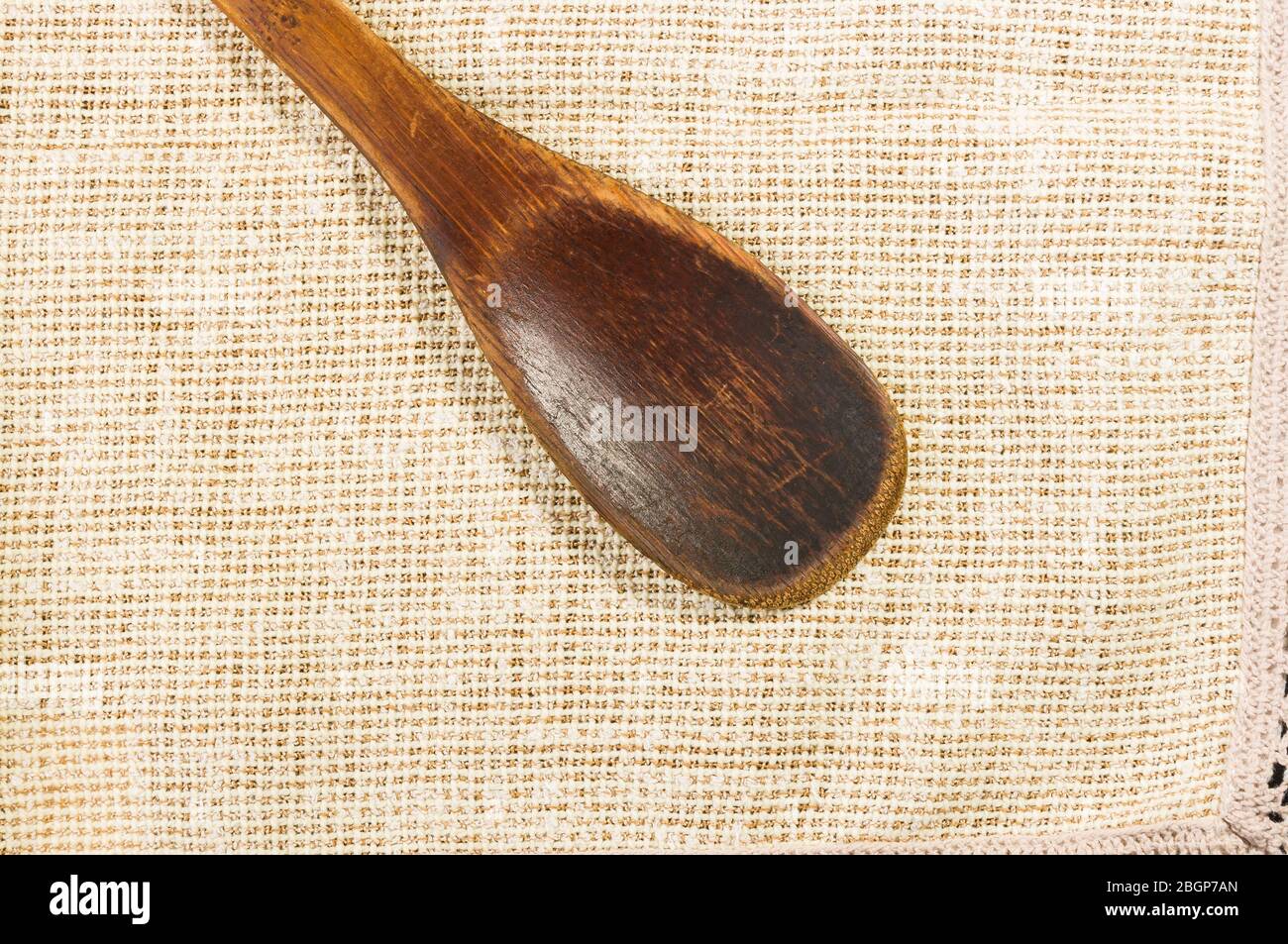 rustic coarse canvas fabric and a worn wooden spoon, close-up ...