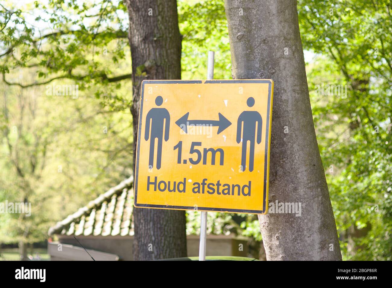 Yellow warning sign with the text in dutch: 1.5 meter, keep distance ...