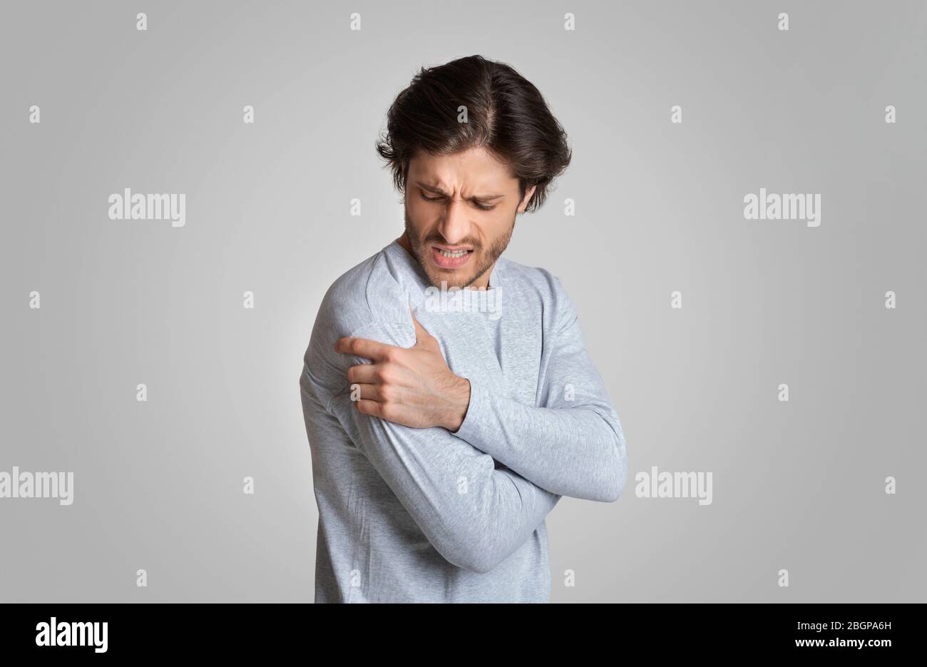 Handsome guy feels pain in his shoulder Stock Photo - Alamy