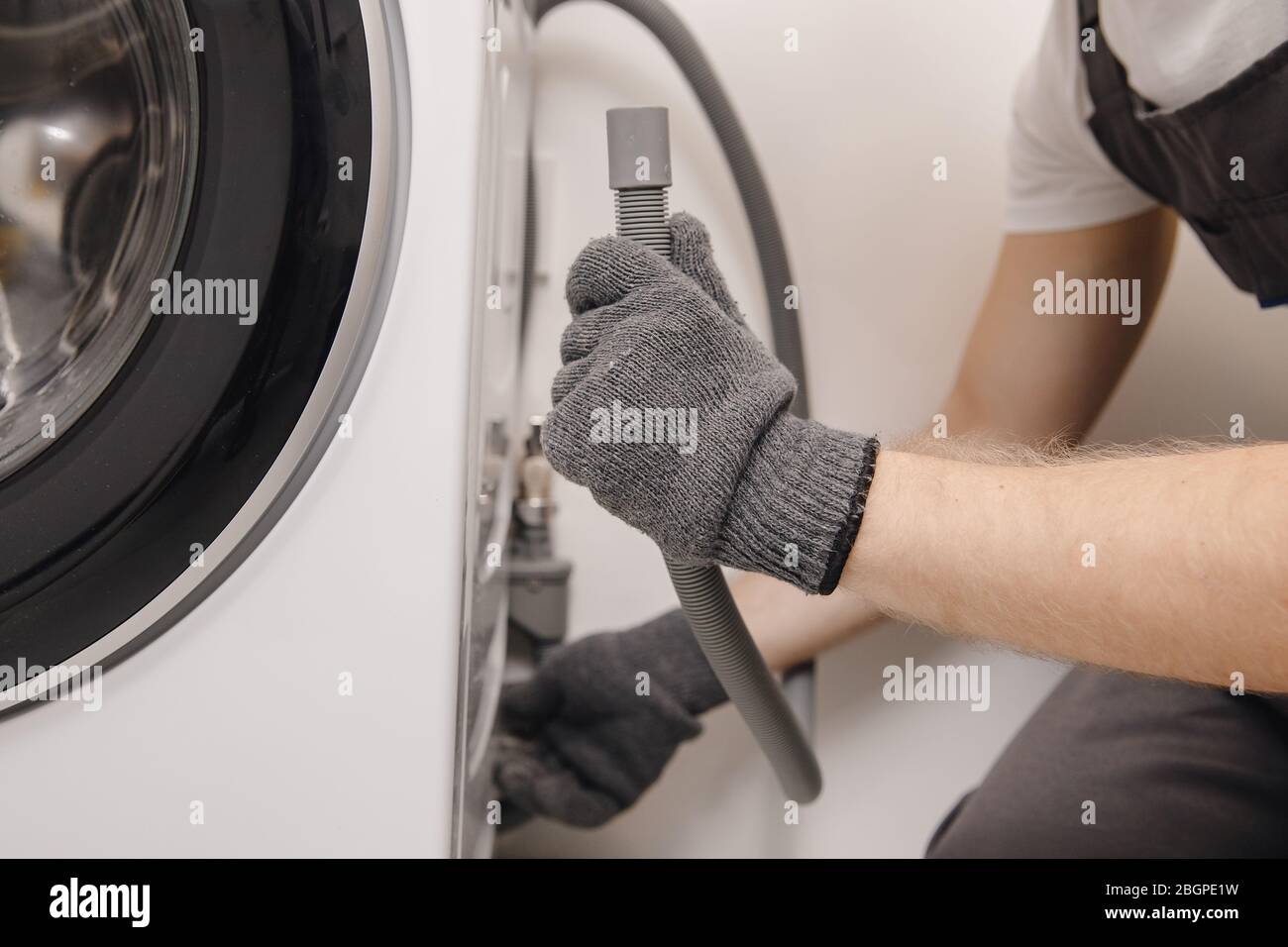 Plumber repairing washing machine, working man fixing connects pipe to ...