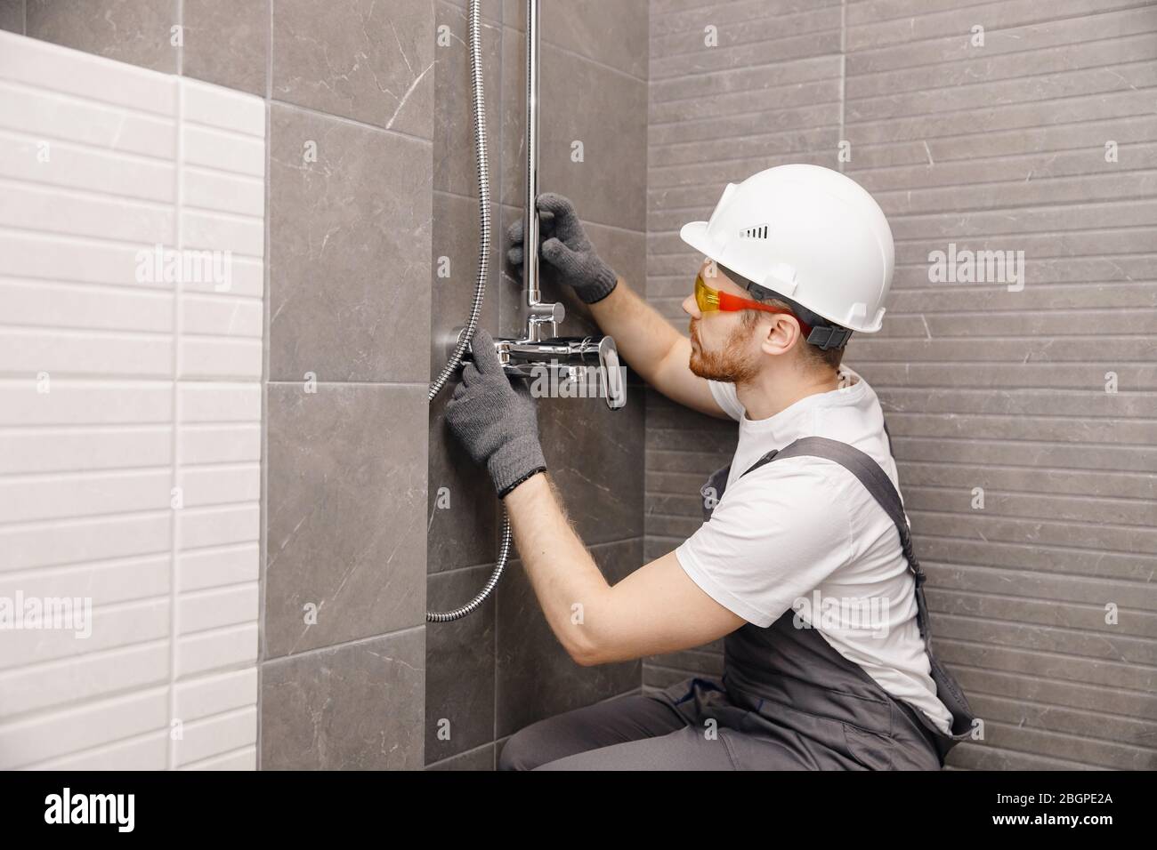 Plumber installing water taps shower stall, work in bathroom Stock ...