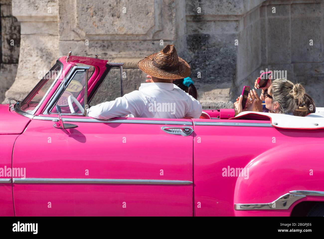 Women tourists in Havana, Cuba taking a ride in a classic pink ...